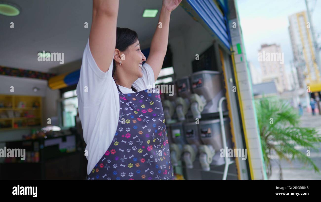 Female Business Owner of Local Store opening garage storefront. Young ...