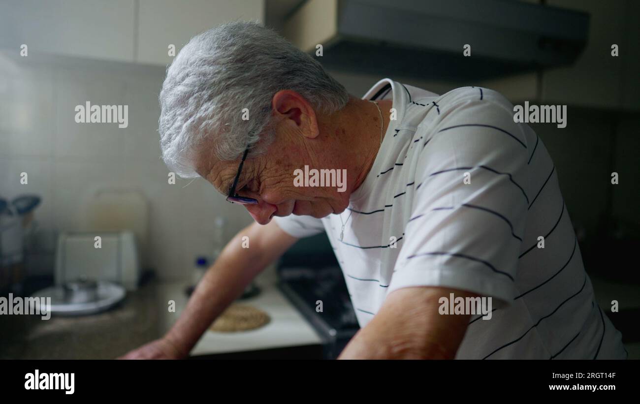 Mature man standing at kitchen counter struggling with old age and ...