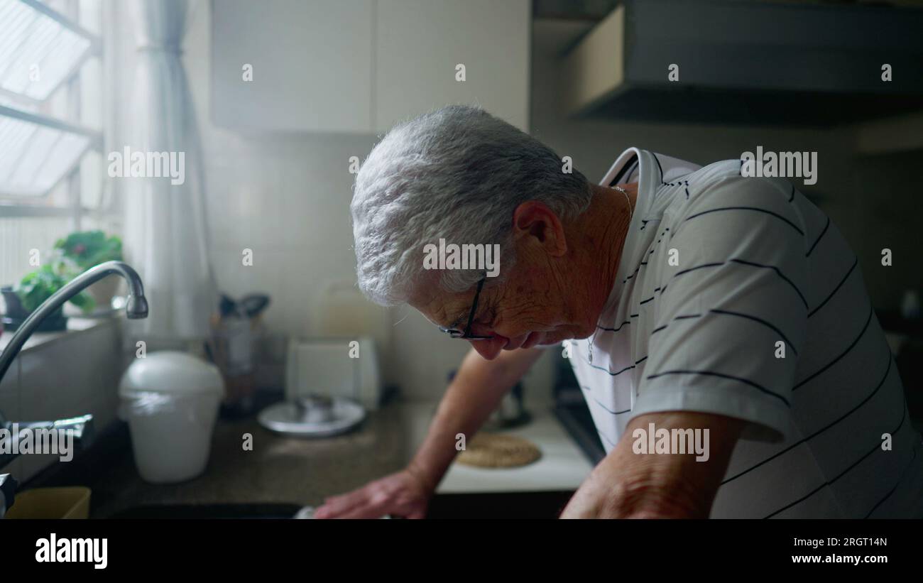 Mature man standing at kitchen counter struggling with old age and ...
