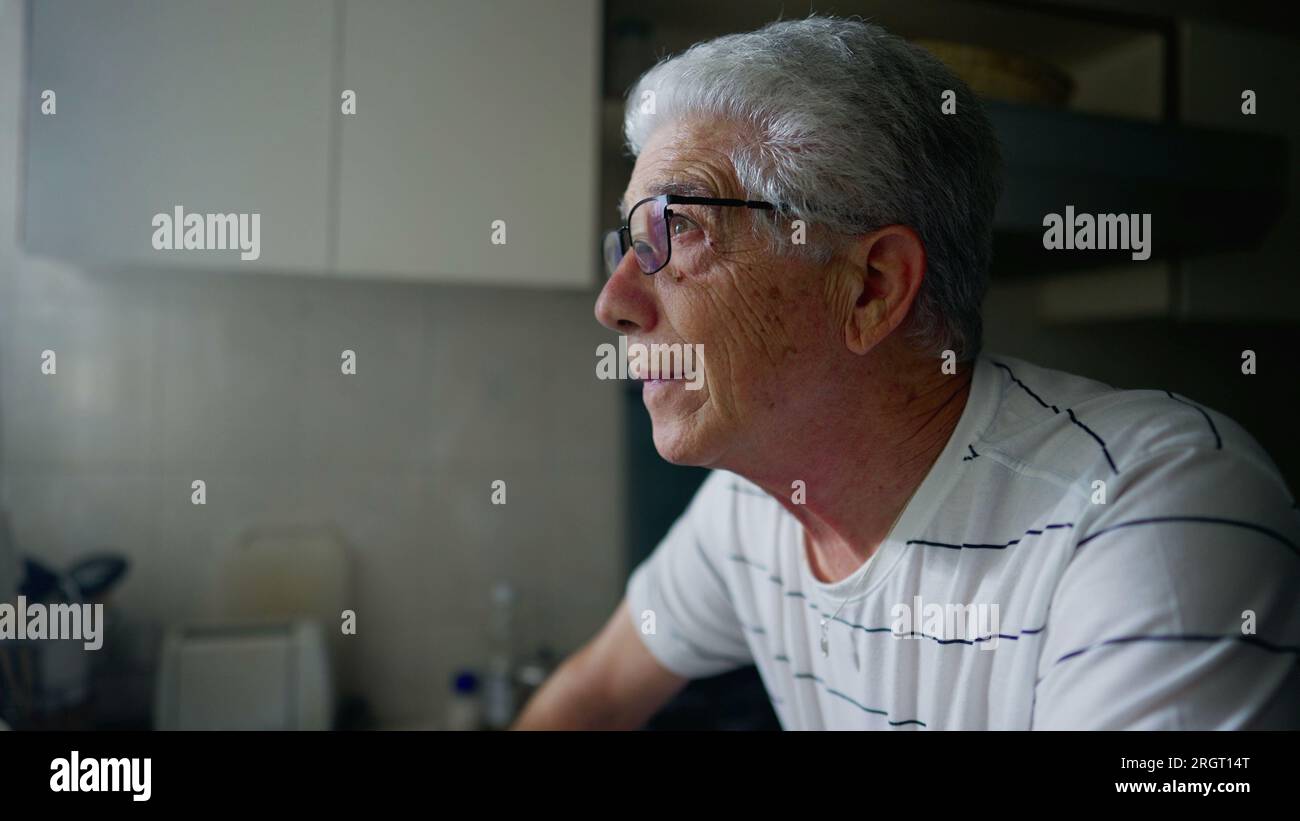 Mature man standing at kitchen counter struggling with old age and ...