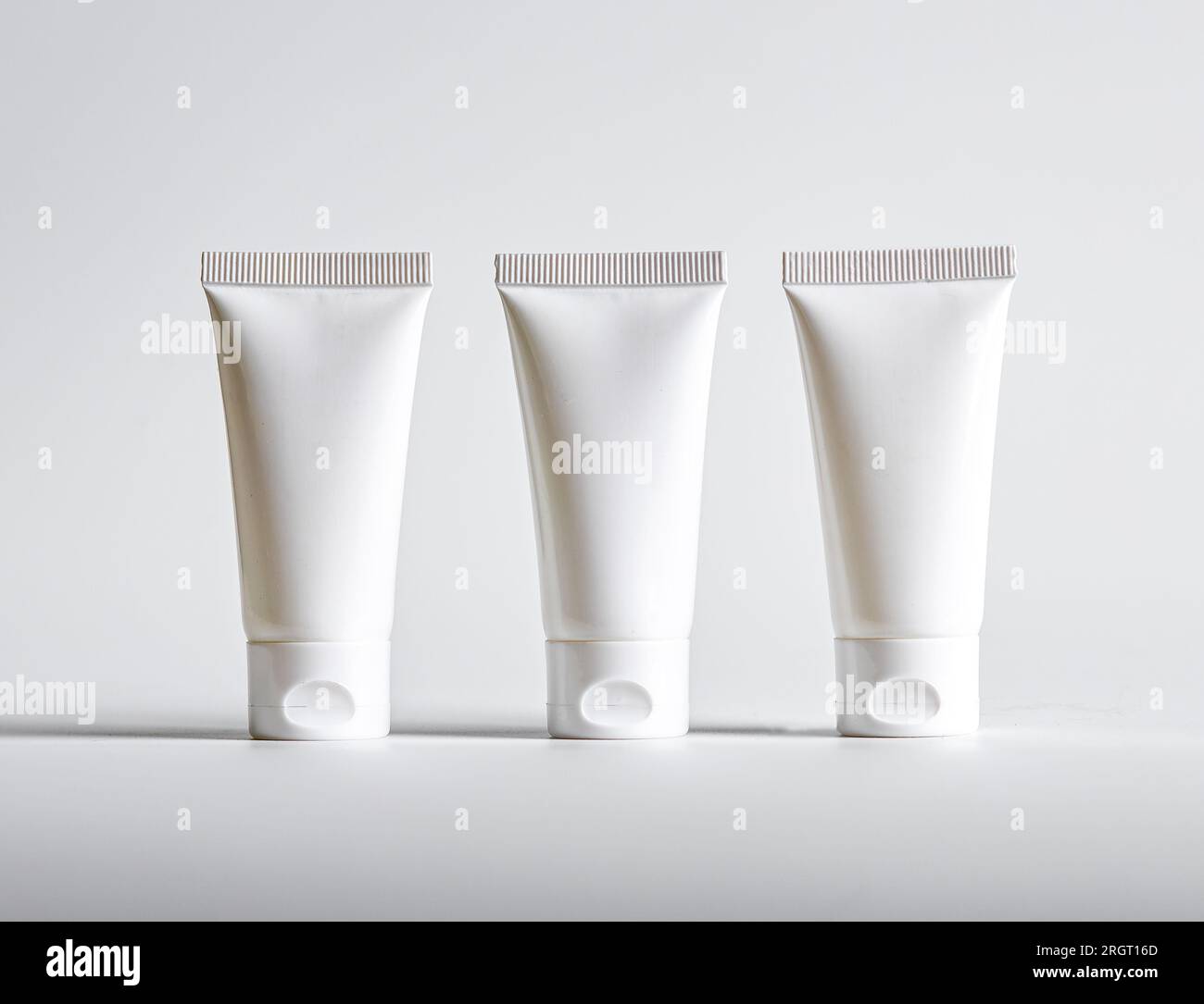 Three cream tubes row mockups Stock Photo - Alamy