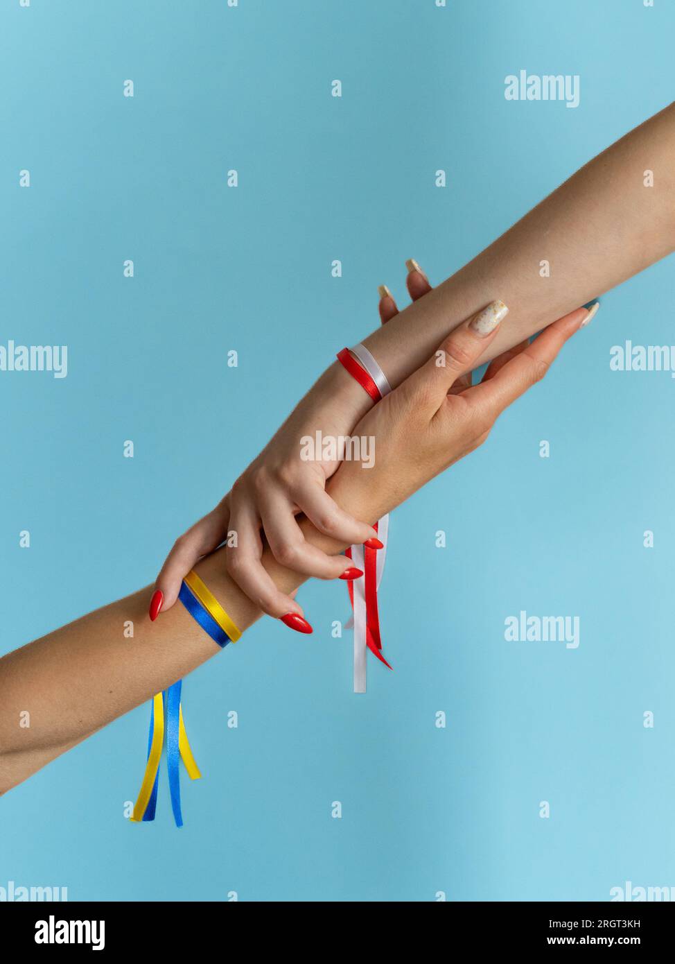 Women's hands with tied ribbons in colors of flag of Ukraine and Poland ...