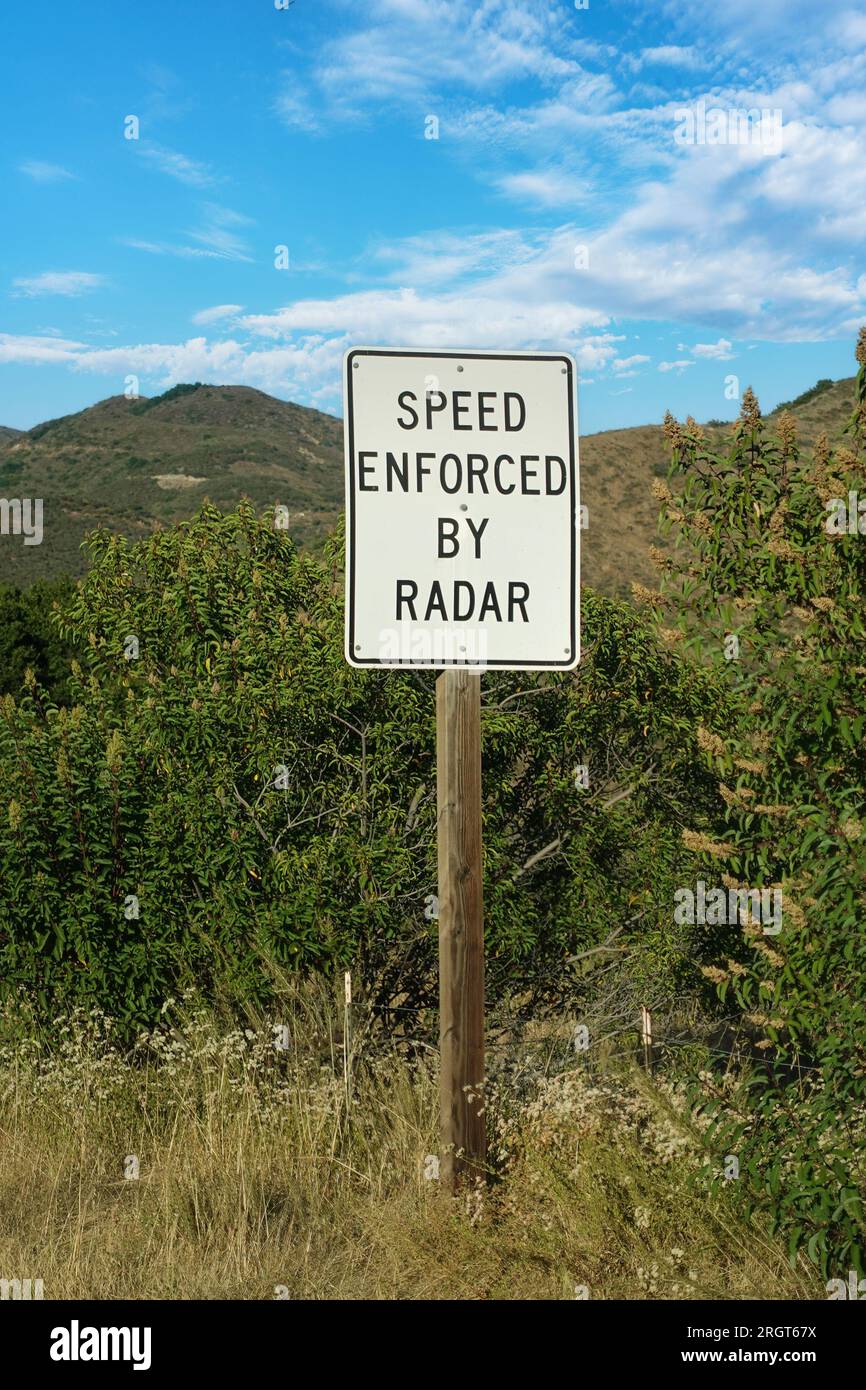A white speed enforced by radar road sign alongside rural highway Stock ...