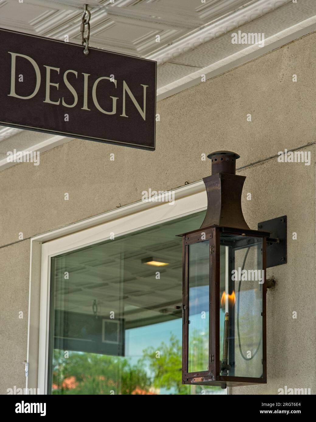 Gas lit lantern mounted on storefront with ‘Design’ sign hung from ...
