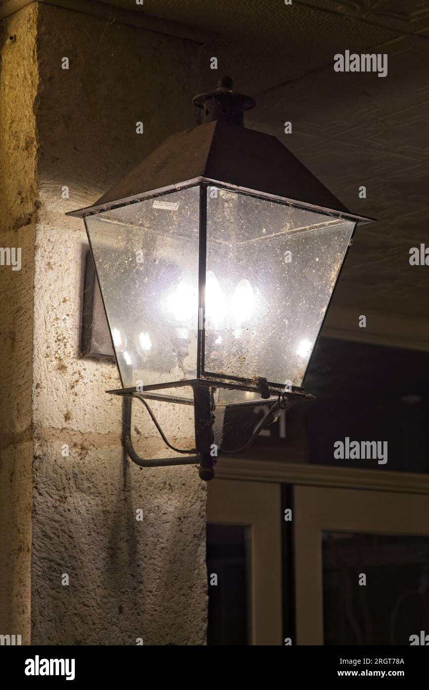 Lit lantern mounted to limestone block wall at dusk Stock Photo - Alamy