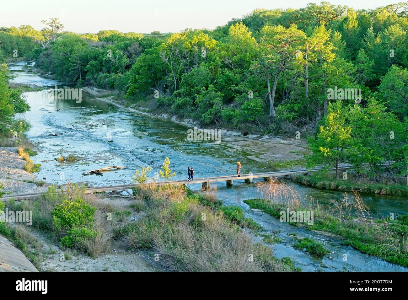 Strolling across river trail bridge over the Guadalupe river running ...