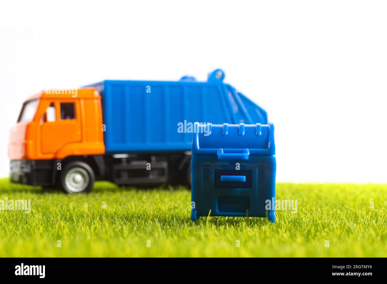 Photo of toy garbage truck with blue colored container on green lawn ...