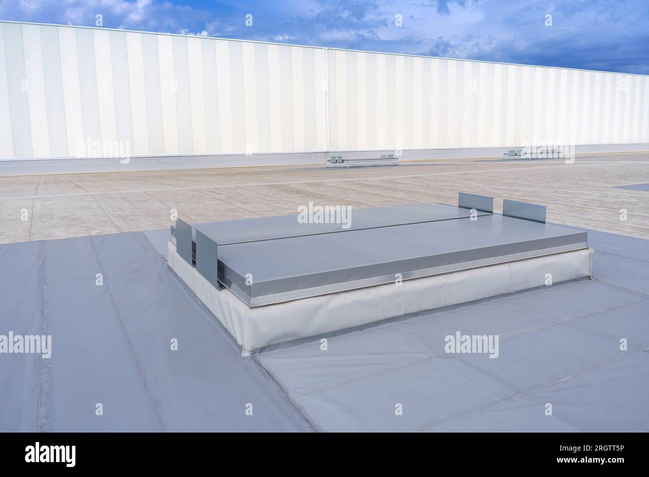 White metal sheet rooftop wall on commercial building with blue sky ...