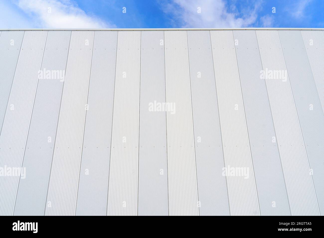 White metal sheet rooftop wall on commercial building with blue sky ...