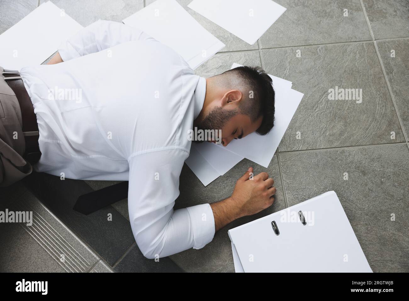 Unconscious man with scattered folder and papers lying on floor after ...