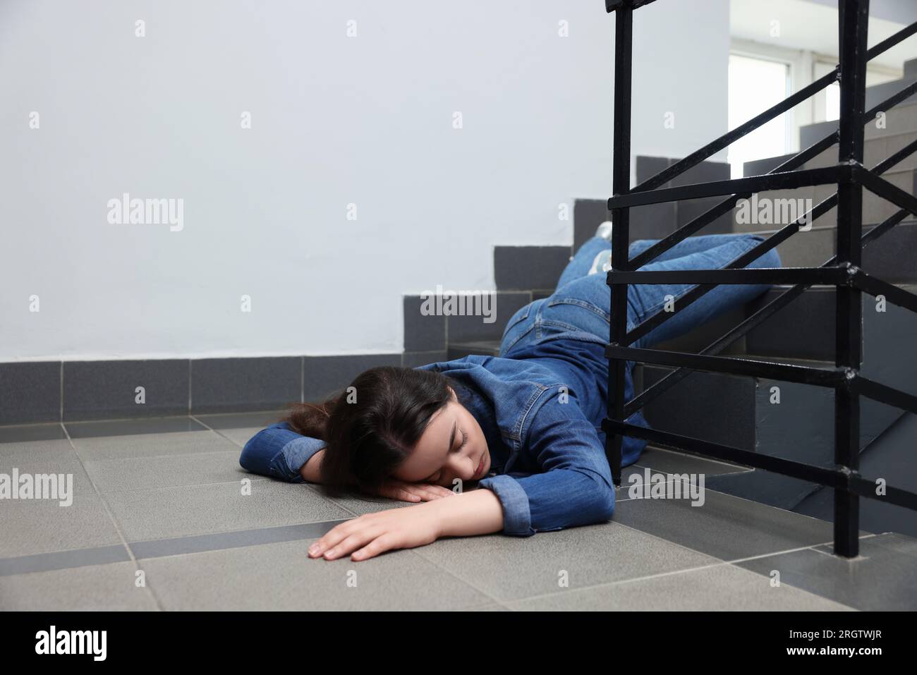 Unconscious woman lying on floor after falling down stairs indoors ...