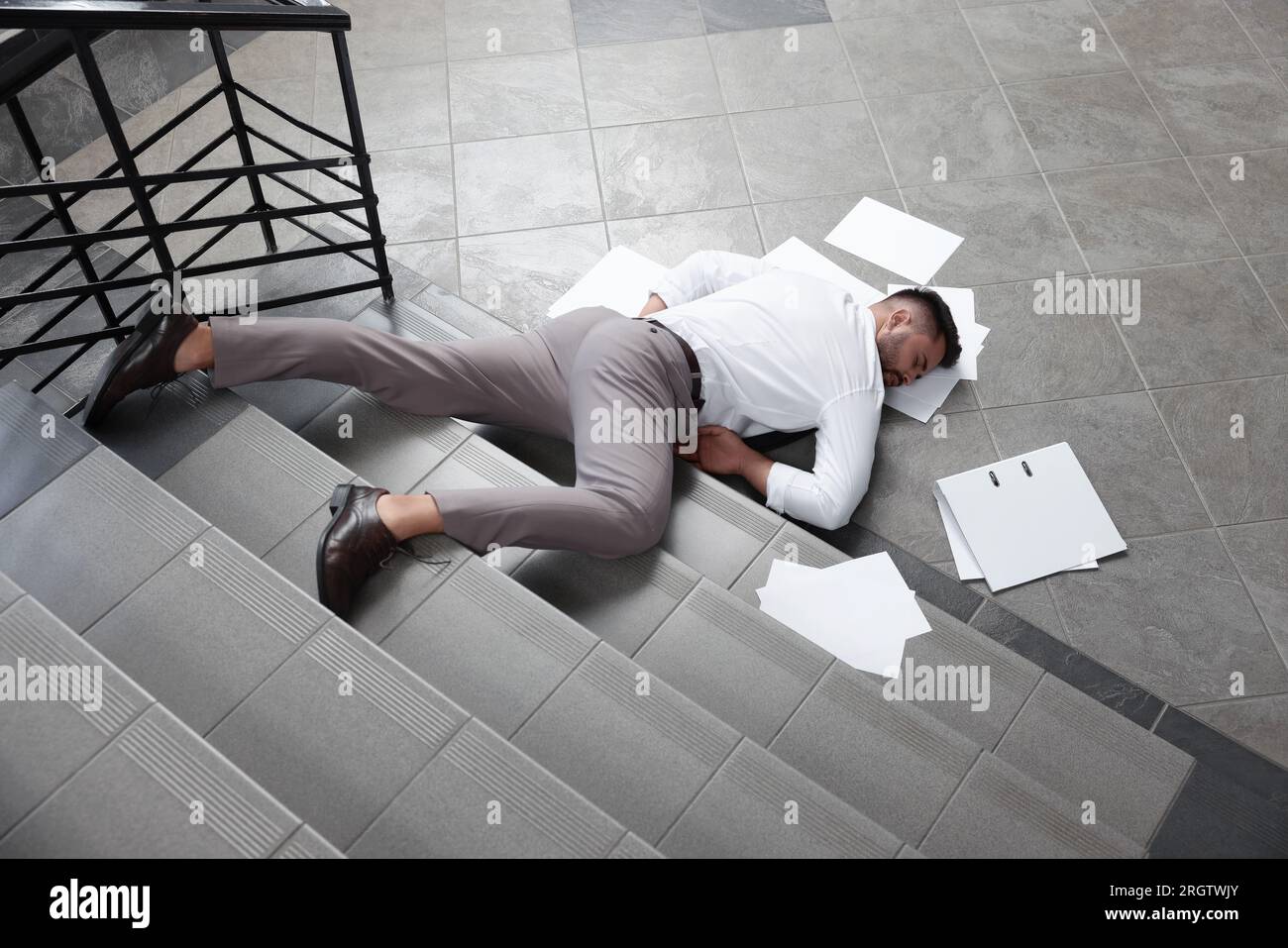 Unconscious man with scattered folder and papers lying on floor after ...