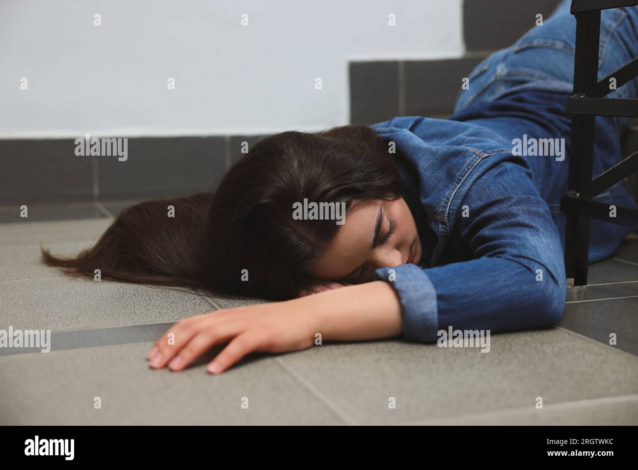 Unconscious woman lying on floor after falling down stairs indoors ...