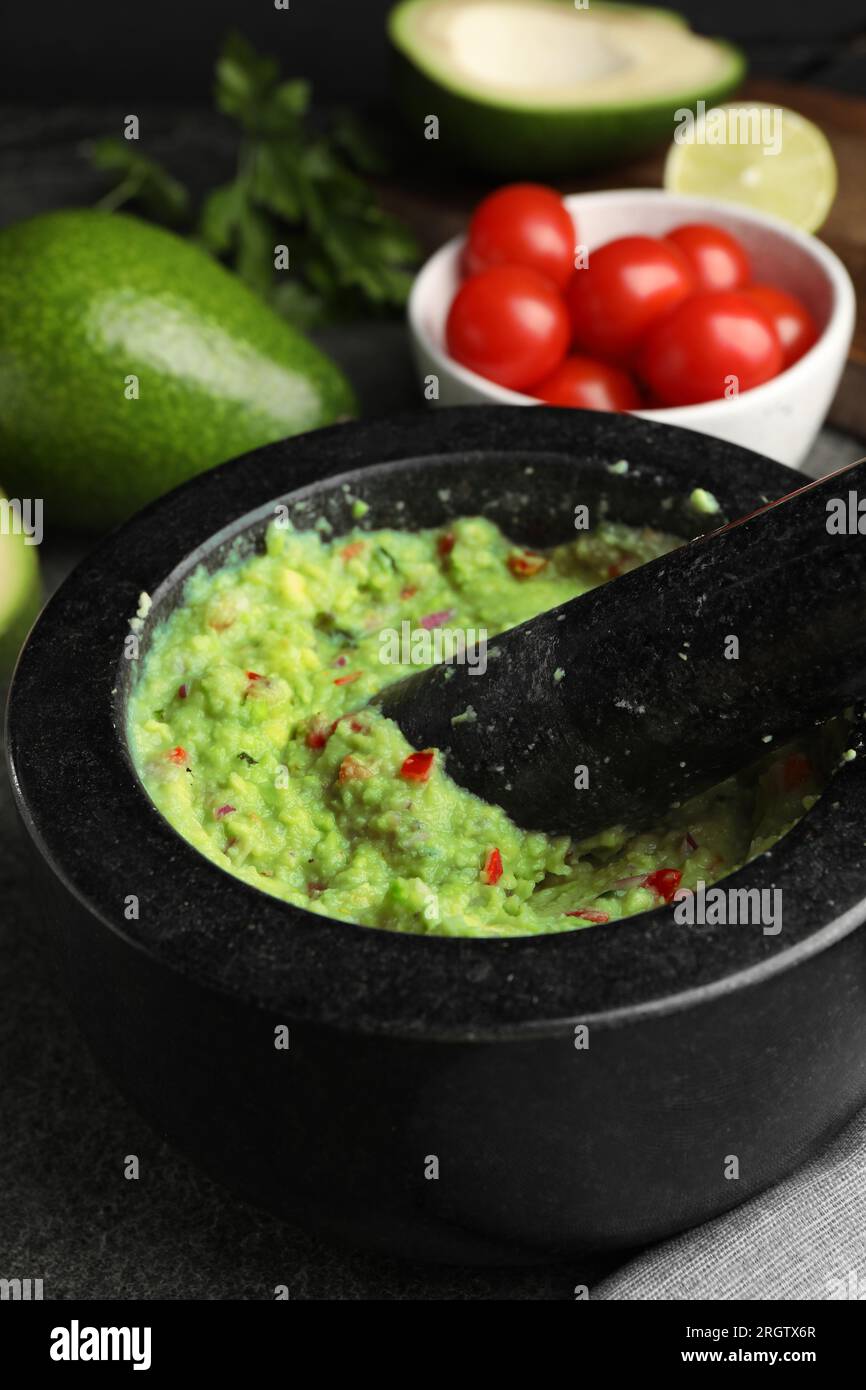 Mortar with delicious guacamole and ingredients on table Stock Photo ...
