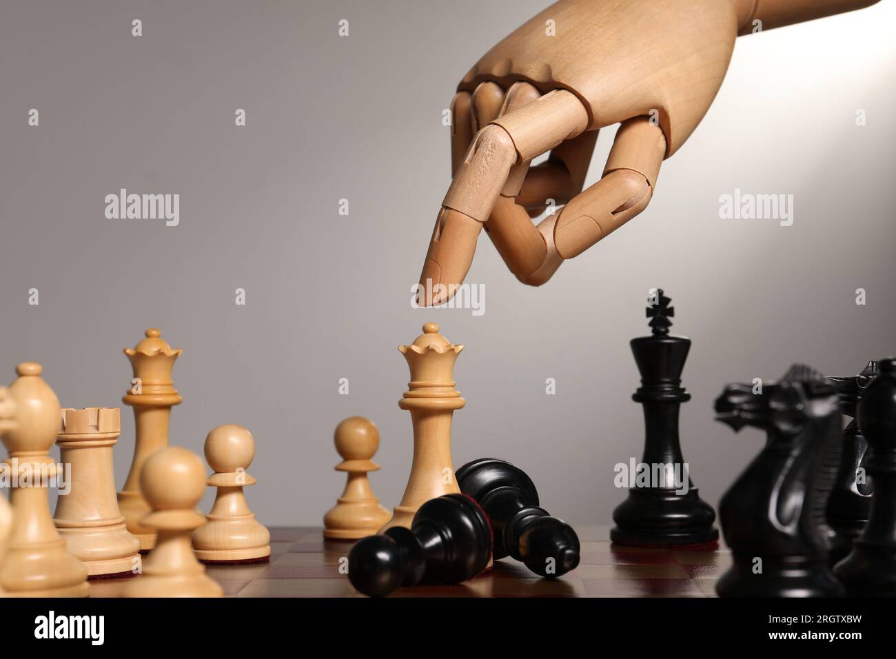 Robot moving chess piece on board against light grey background ...