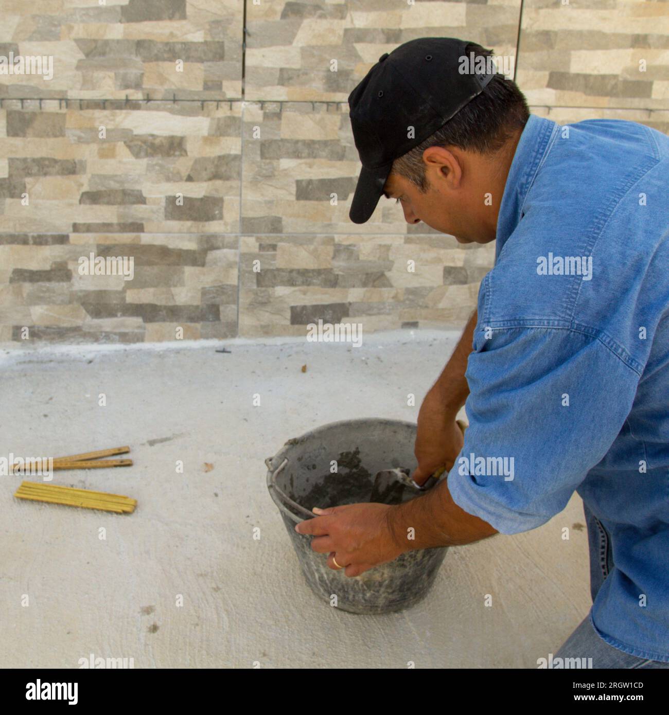 Image of a bricklayer mixing cement and glue in a bucket. Manual work ...