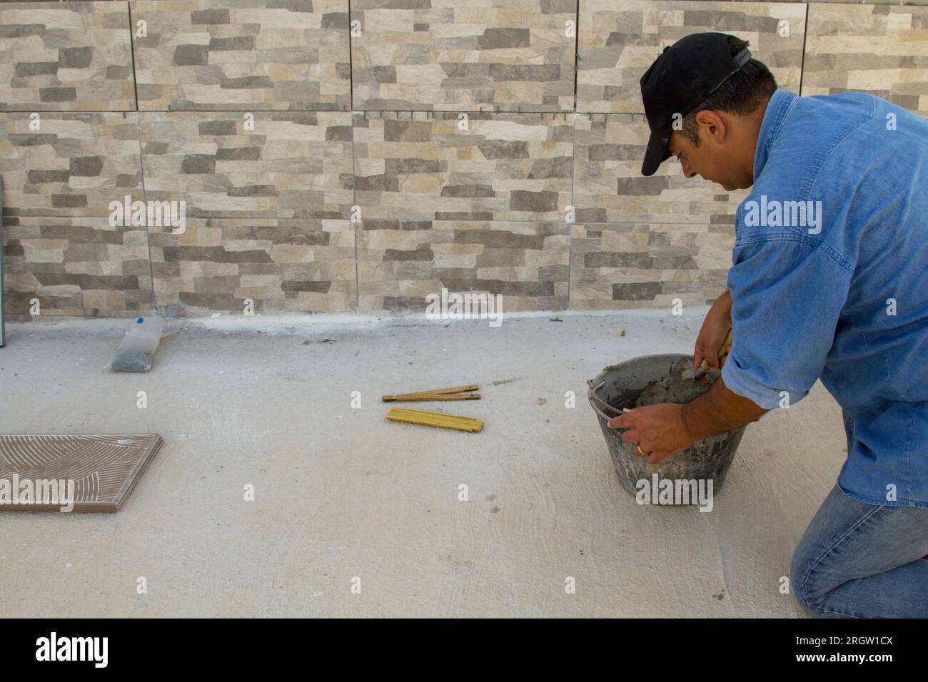 Image of a bricklayer mixing cement and glue in a bucket. Manual work ...