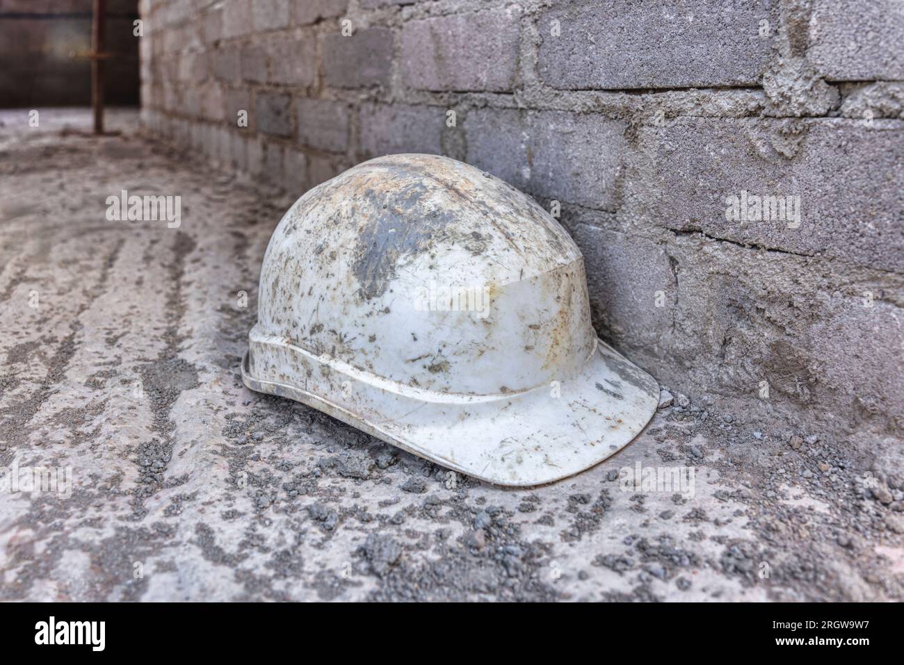 scruffy hardhat on the floor covered in a splash of concrete cement ...