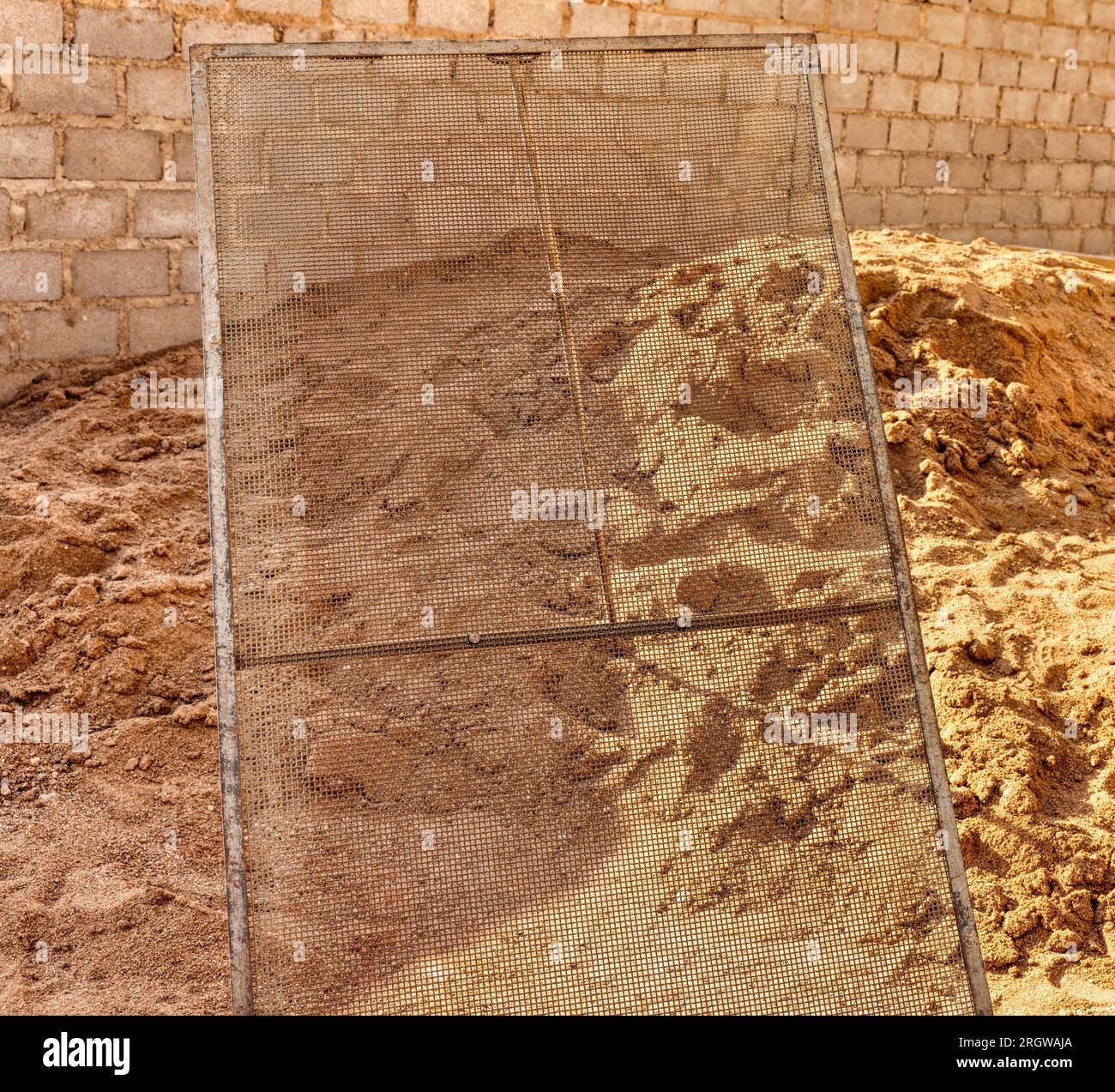 sieving in front of a pile of sand on a construction site, behind a ...