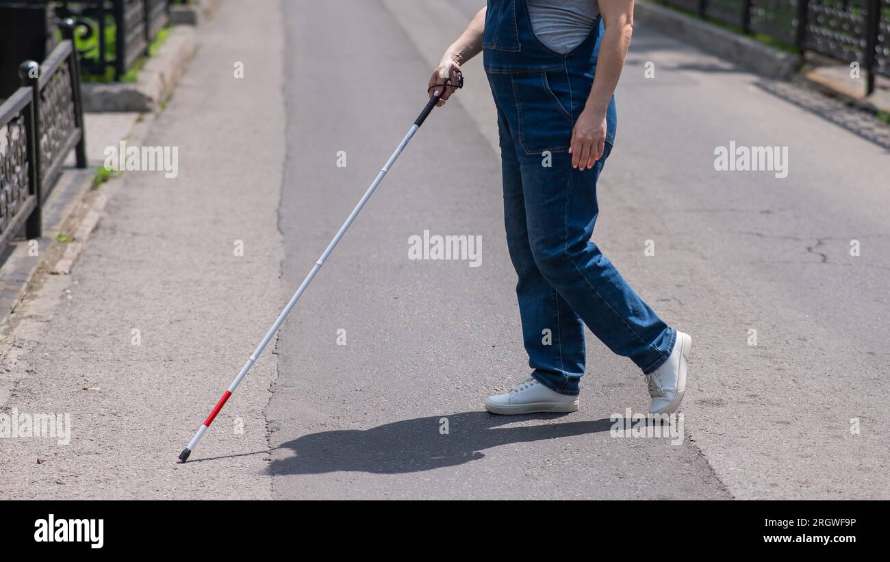 Blind pregnant woman crosses the street with the help of a tactile cane ...