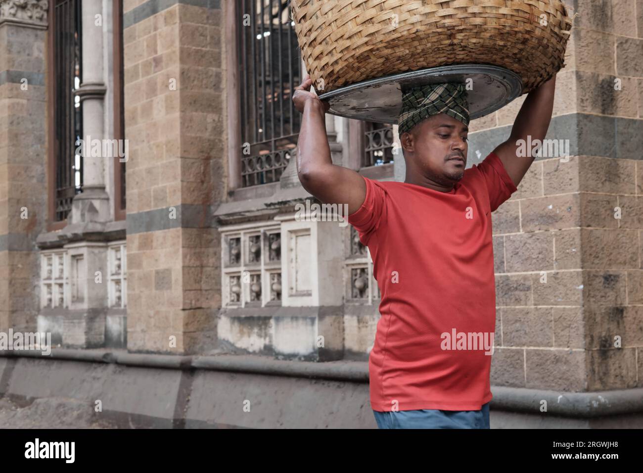 A porter with a basket of fish on his head, outside Chhatrapati Shivaji ...