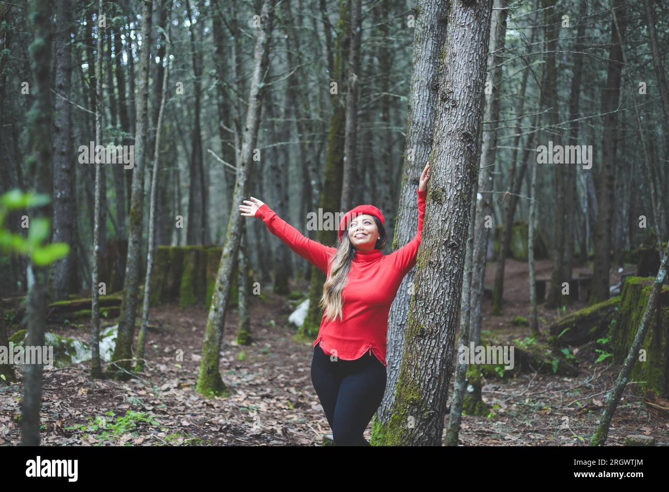 Woman with a pensive attitude admiring the forest leaning against a ...