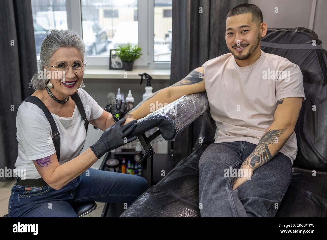 Tattoo master wotking on a tattoo for the male client Stock Photo - Alamy