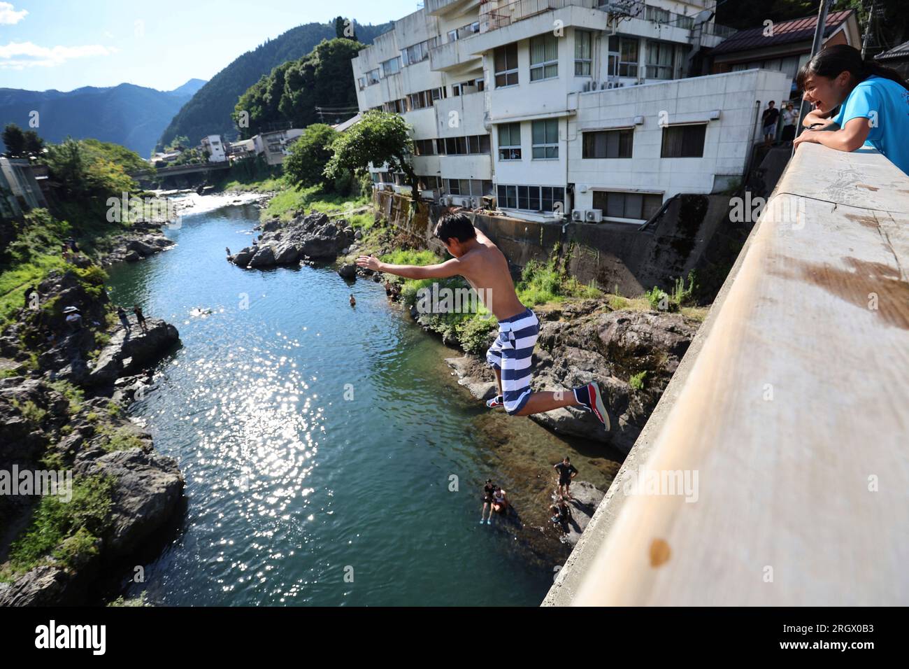 Boy participants jump from the Shinkyo Bridge during Gujo-Hachiman Bridge Diving to beat the ...