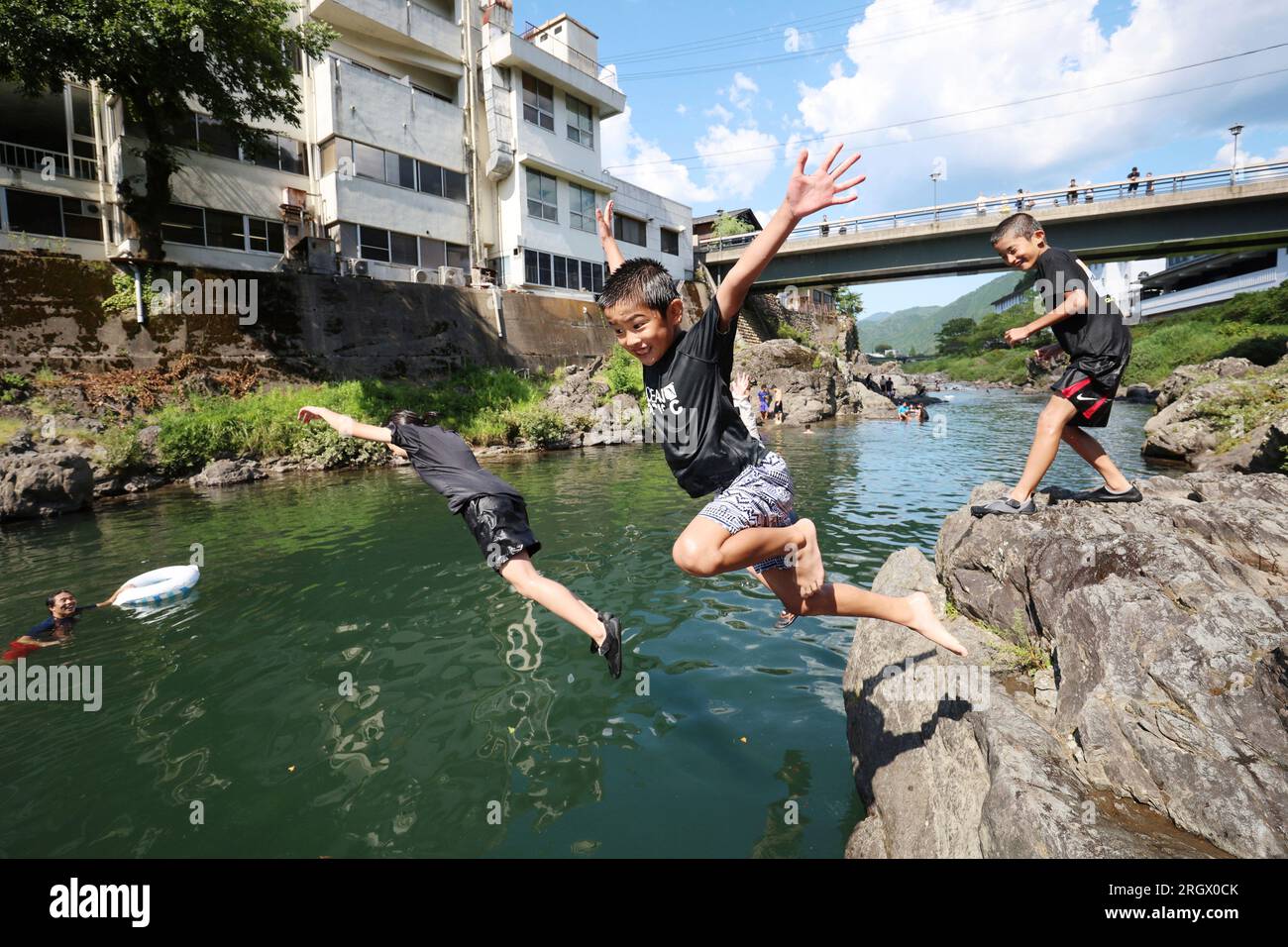 Boy participants jump from the Shinkyo Bridge during Gujo-Hachiman Bridge Diving to beat the ...