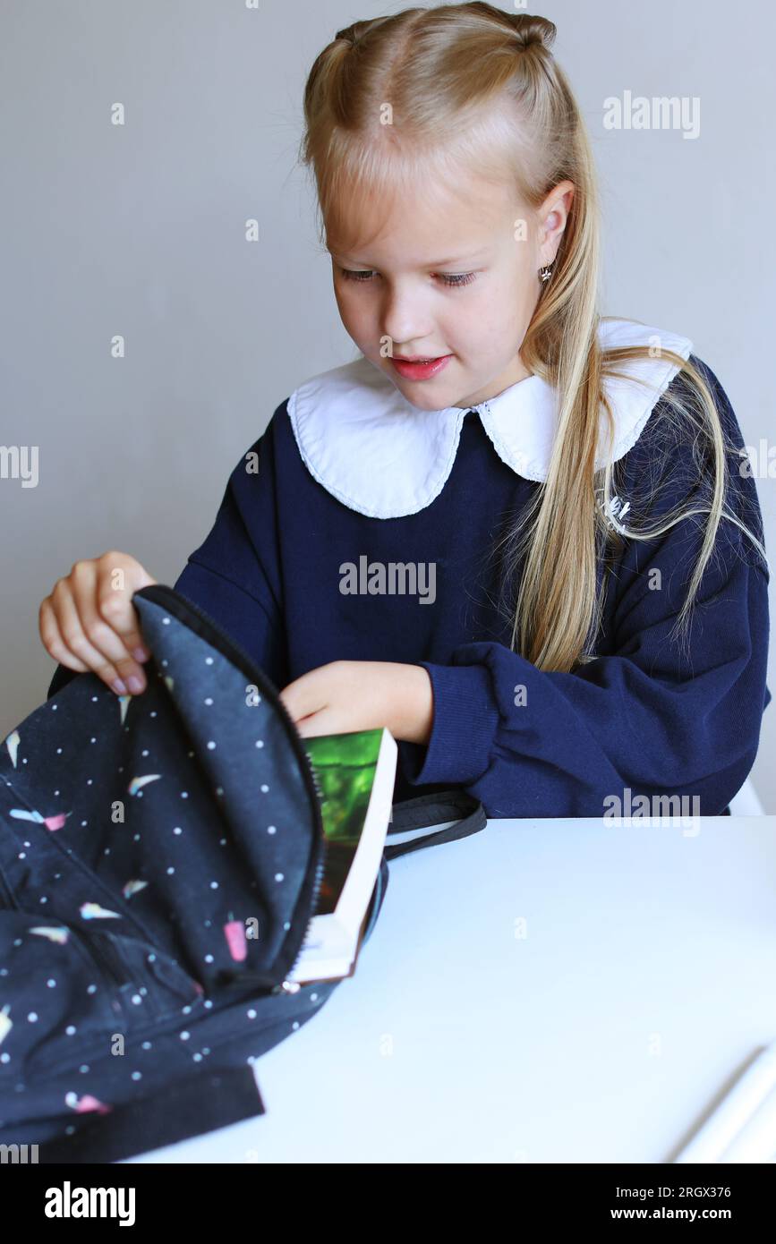 child put books and notes into backpack. School supplies.Back to school ...