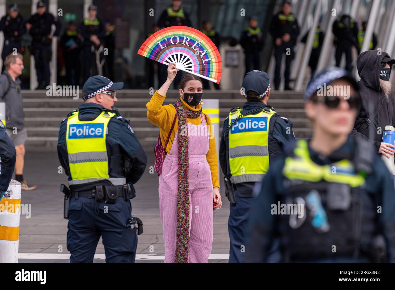 A pro-LGBT protester with a rainbow trans pride fan stand behind a ...
