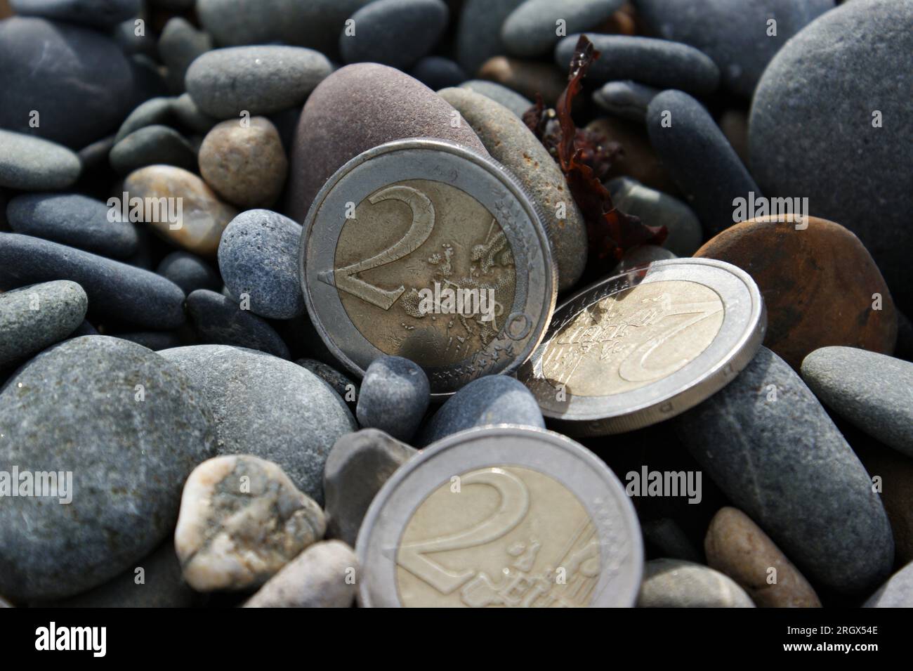 Spilled 2 euro coins on the stones. Spilled money Stock Photo - Alamy