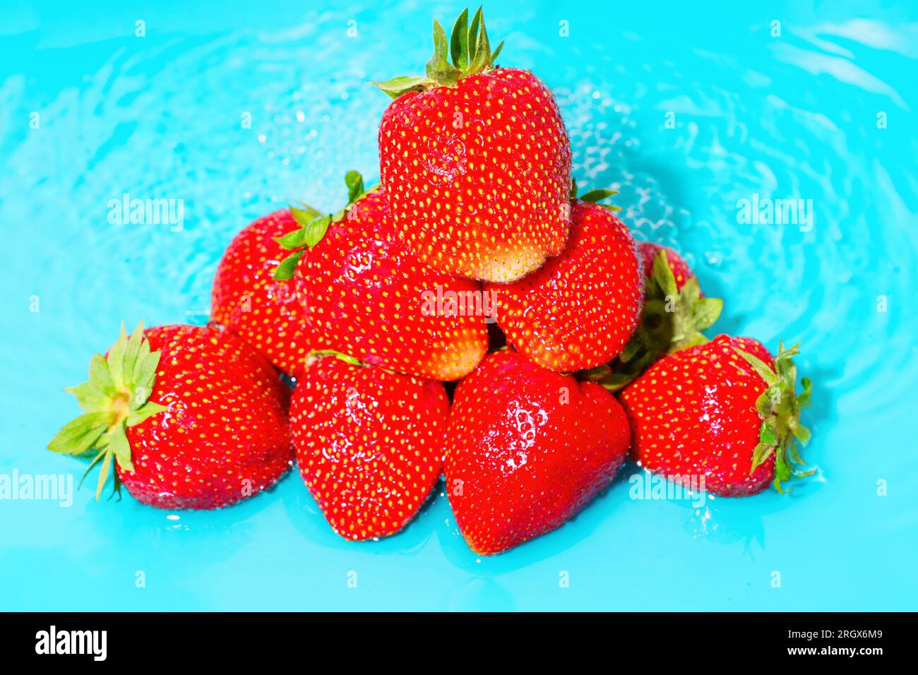 Pile of fresh, juicy strawberries partly submerged in shallow, crystal ...