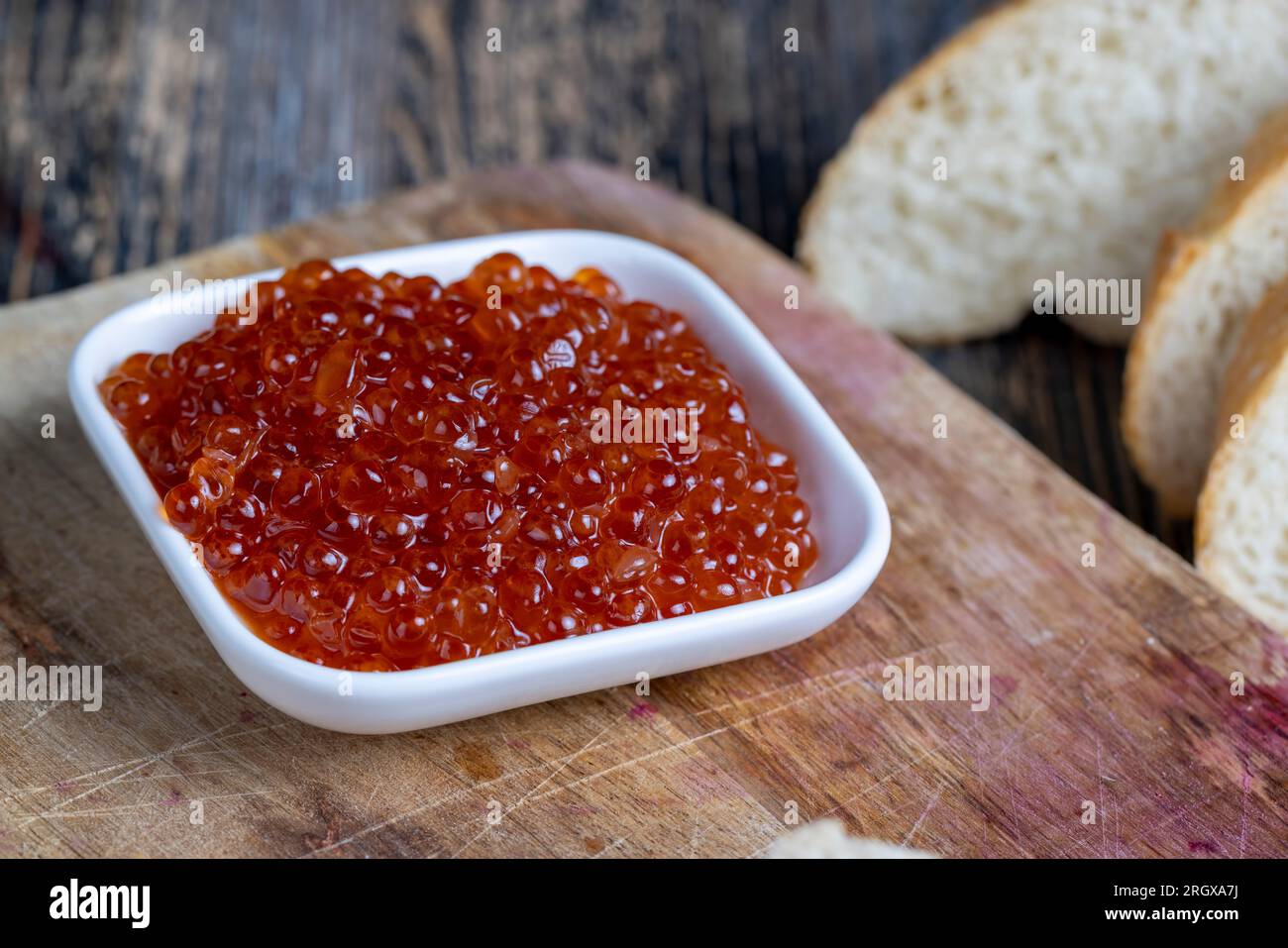 red salmon or trout caviar with white baguette and butter, making ...