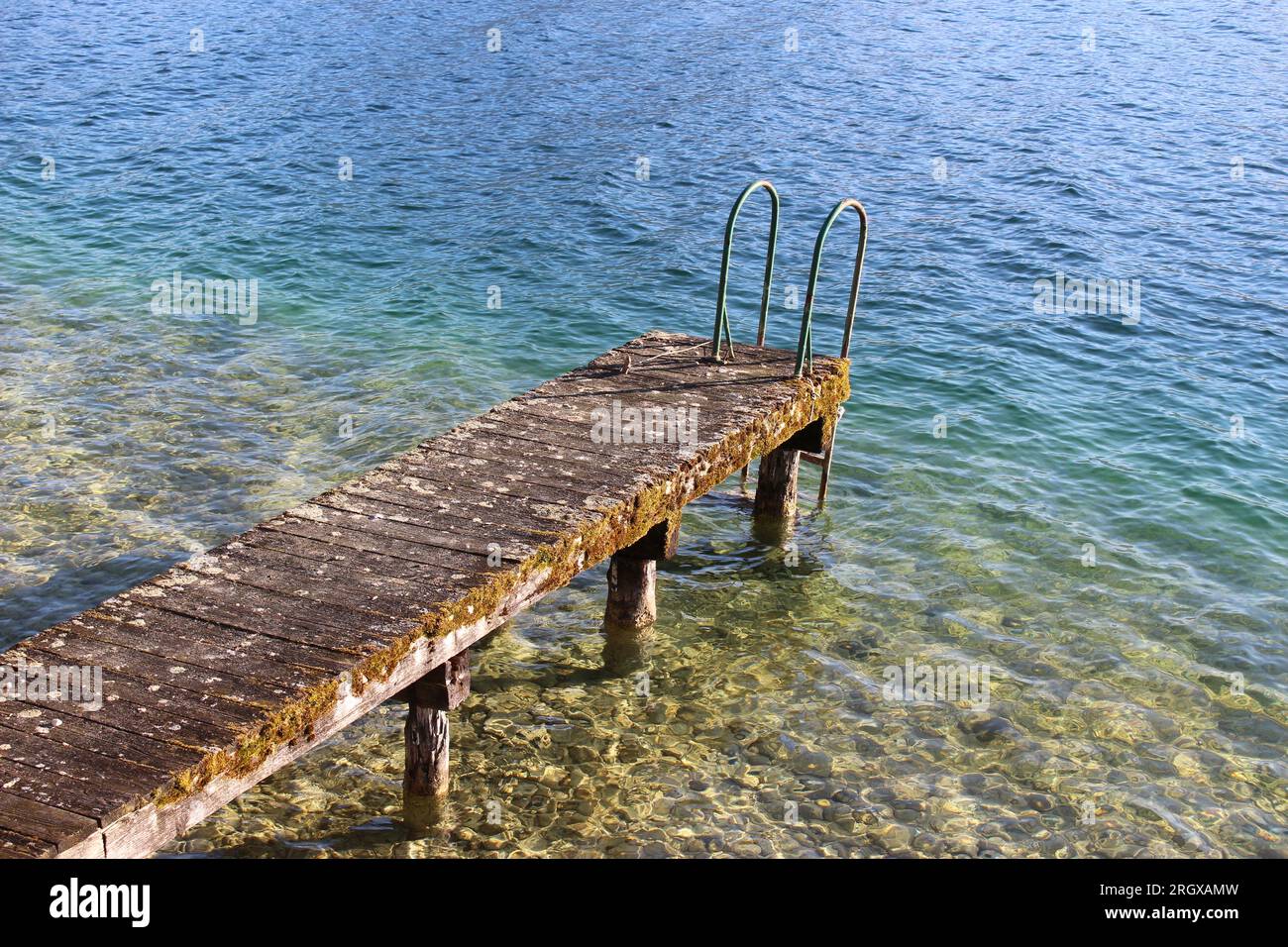 Old mossy wooden pier over turquoise clear waters (Wolfgangsee, Austria ...