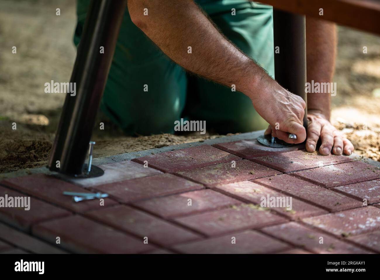 A construction worker bolts a park bench to paving stones Stock Photo ...