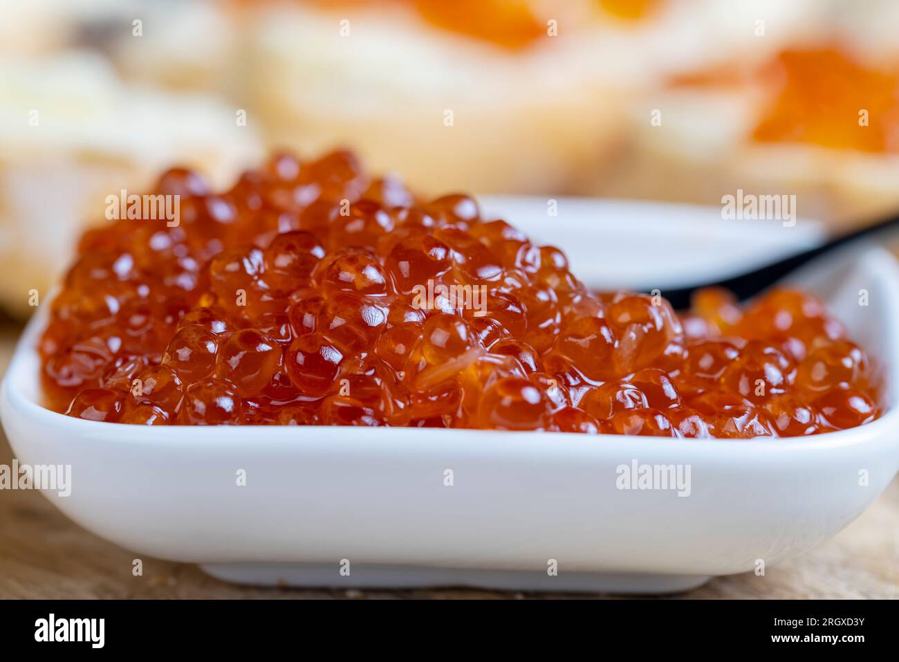 red salmon or trout caviar with white baguette and butter, making ...