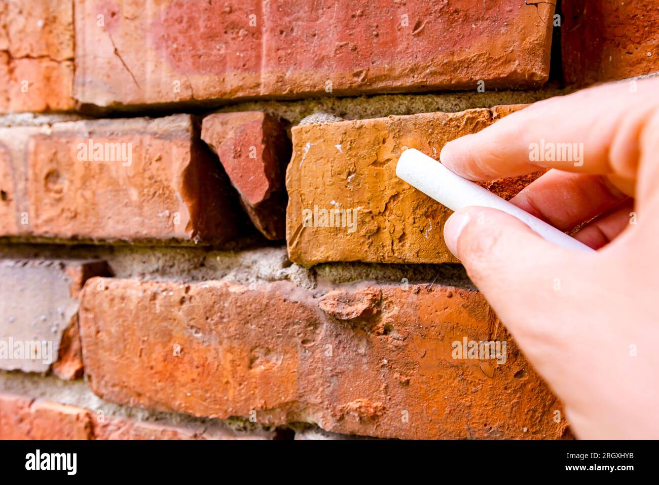 Hand holds white school chalk, ready for writing or drawing on red ...