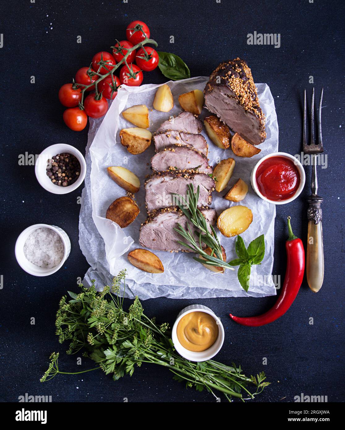 Oven baked pork meat in mustard grains with baked potatoand tomato ...