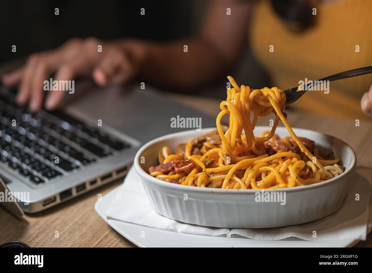 Eating spaghetti while working on laptop at home. Unhealthy food during ...