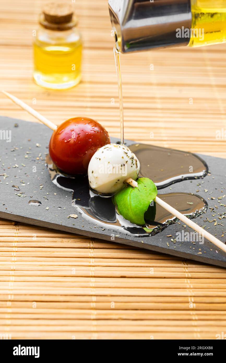 Pouring extra virgin olive oil over a capresse salad skewer. Tomato ...