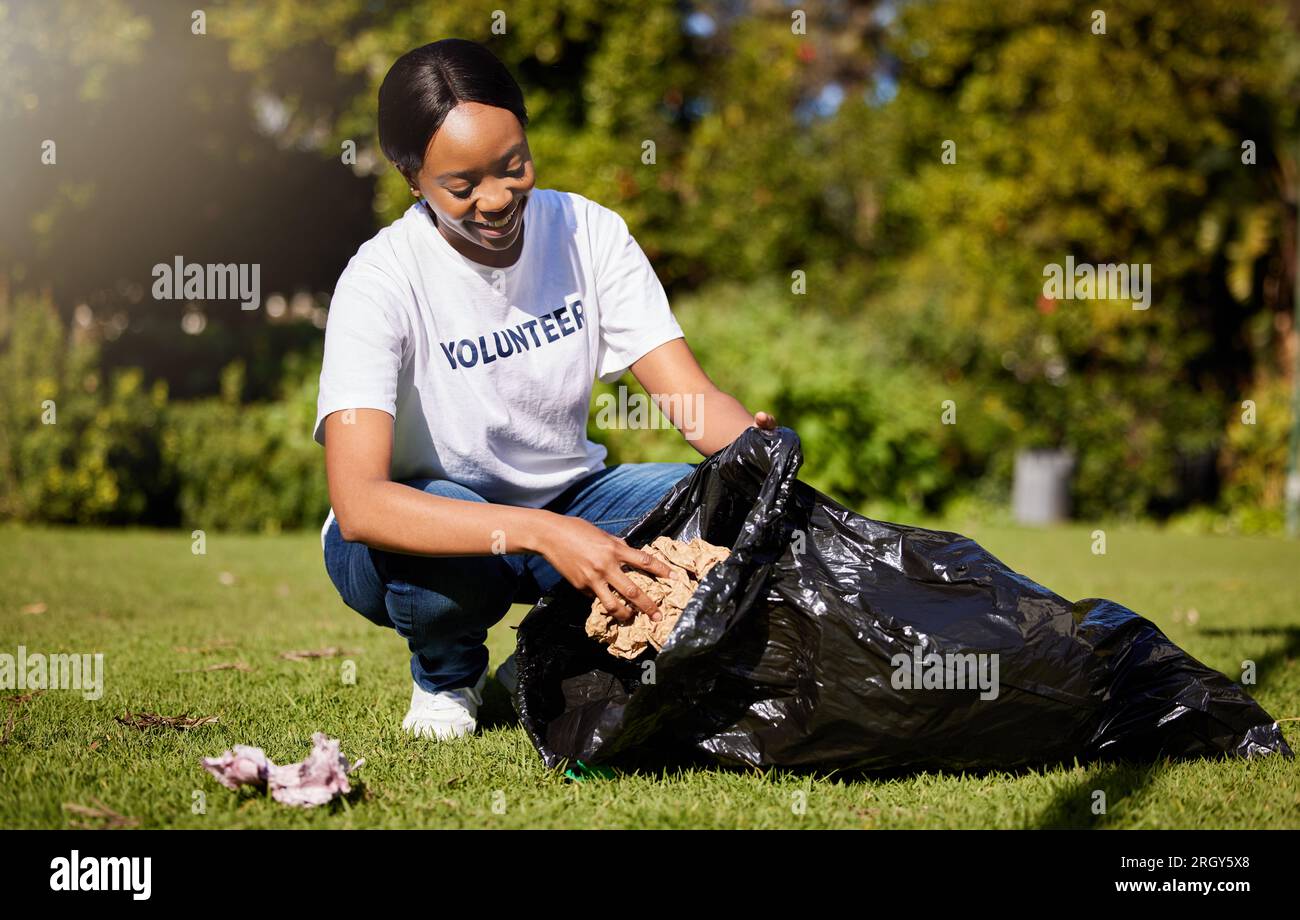 Volunteer, woman and cleaning waste in park for community service ...