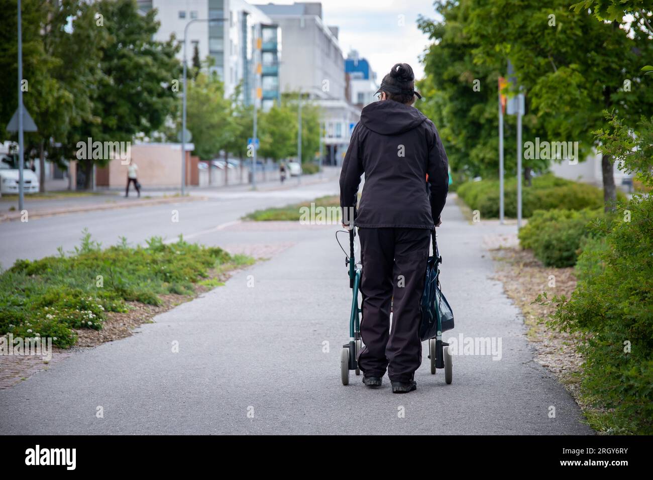 a woman walking on sidewalk with rollator Stock Photo - Alamy