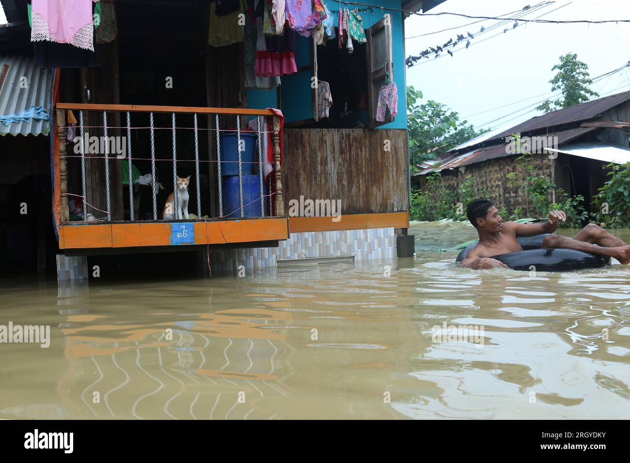 Bago, Myanmar. 12th Aug, 2023. A man sits on a floating tube in flood ...