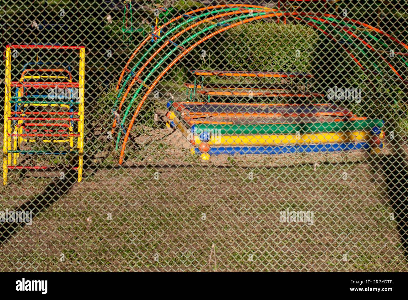 rural playground behind a metal fence, metal mesh fence enclosing a ...