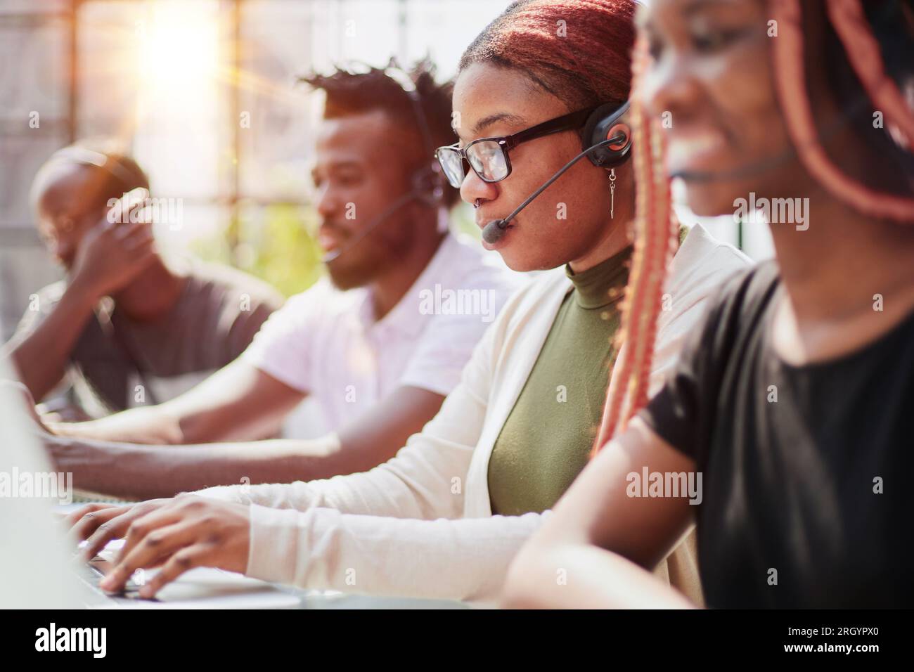 Call Center Operator With Colleagues At Workplace Stock Photo - Alamy