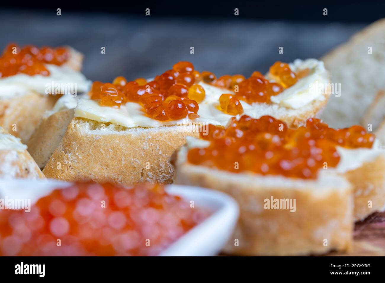 red salmon or trout caviar with white baguette and butter, making ...