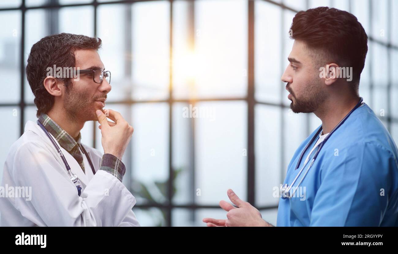 Two doctors men having conversation and one of them has crossed arms ...