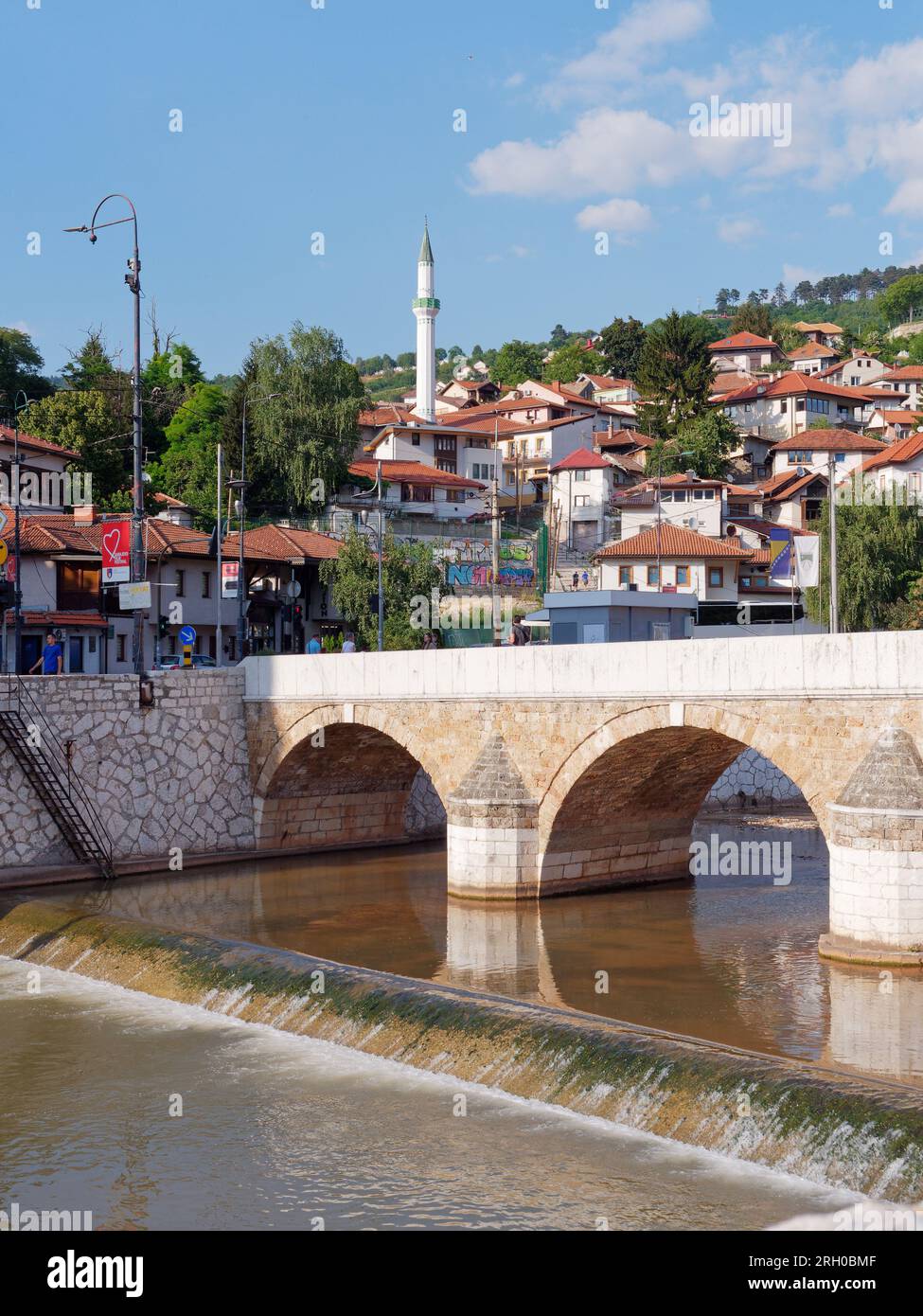 Bridge over the Miljacka river with houses and mosque behind in the ...