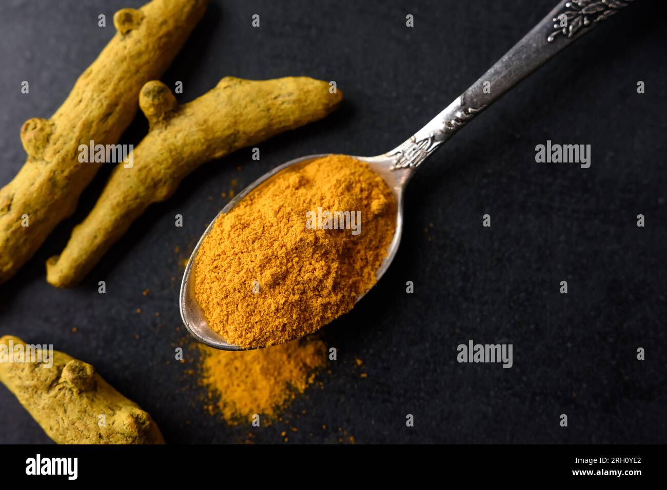 Dried turmeric roots and powder on a spoon Stock Photo - Alamy